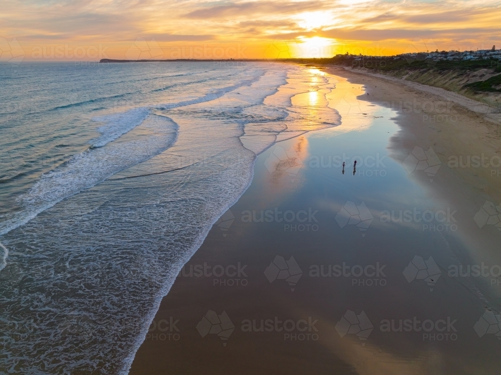 Image of Aerial view of gentle waves on a beach with reflection of a ...