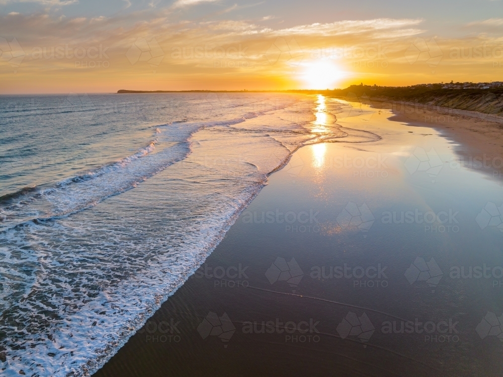 Image of Aerial view of gentle waves on a beach with reflection of a ...