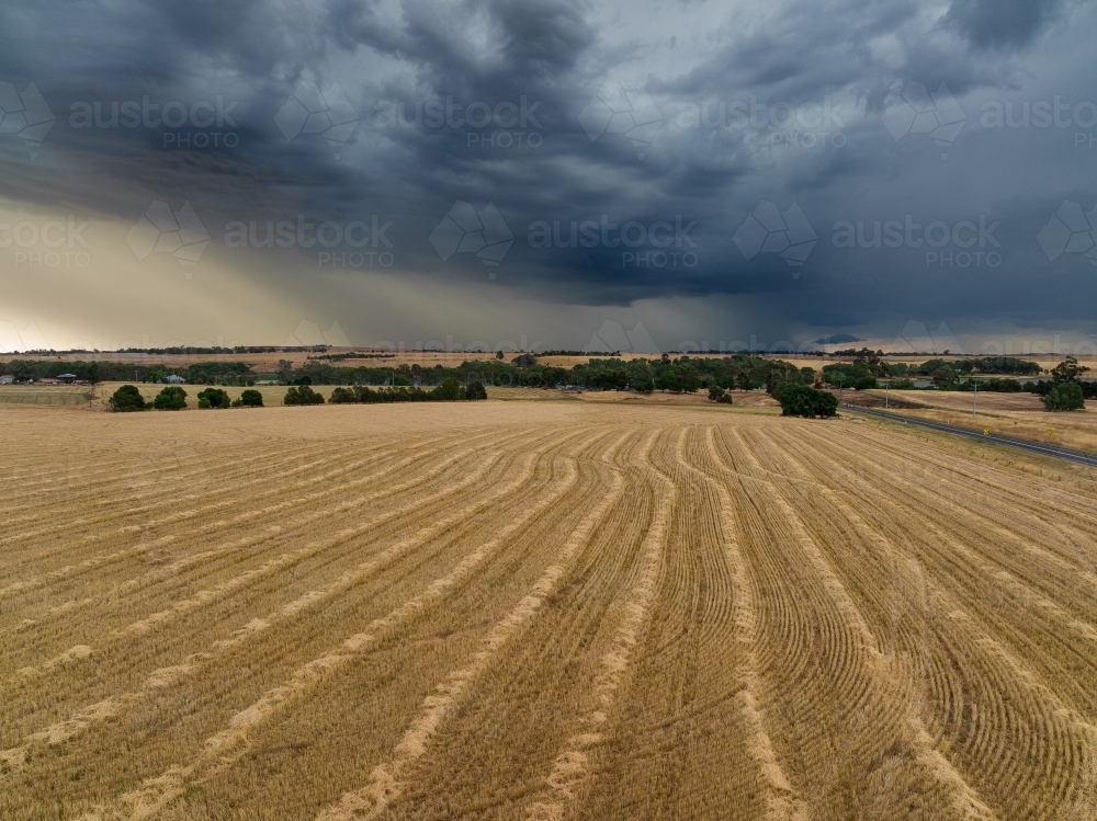 Image of Aerial view of harvester lines in a dry paddock under rain ...