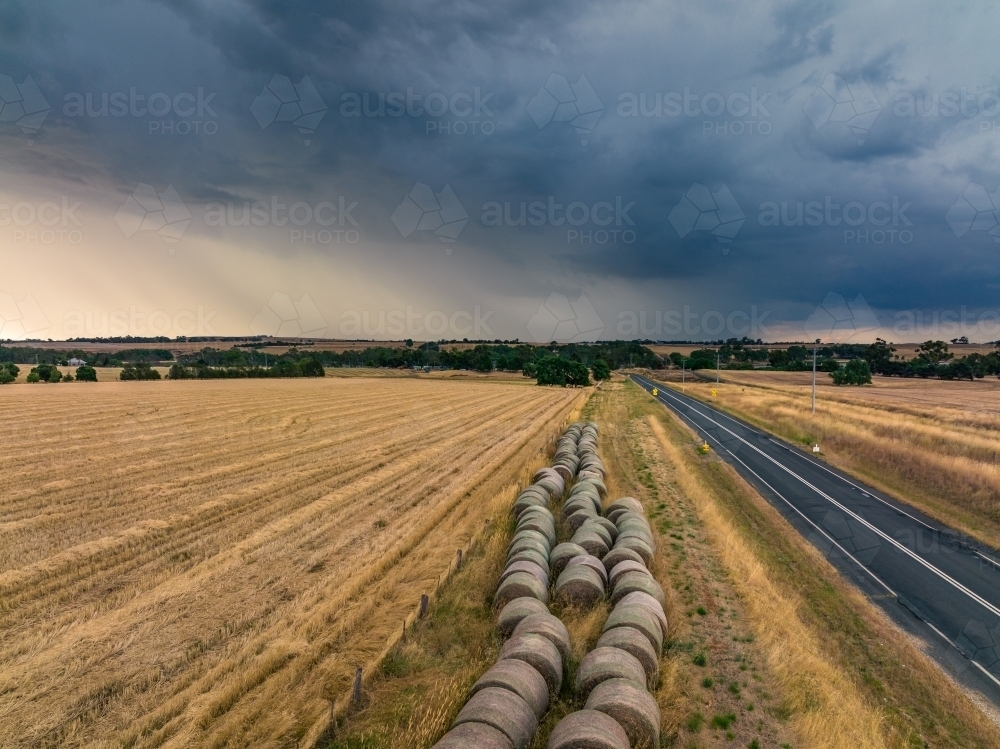 Image of Aerial view of hay bales beside a dry paddock under rain ...