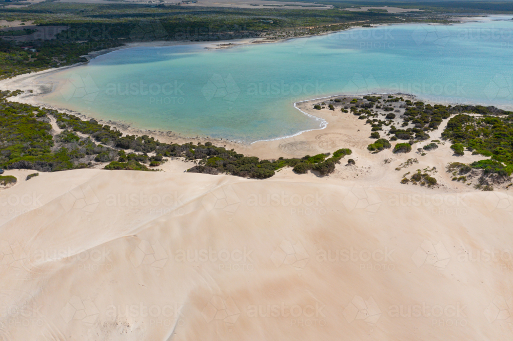 Image of Aerial view of high sand dunes rolling down to blue lagoon ...