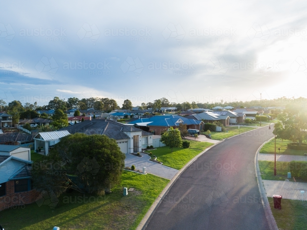 Image of Aerial view of houses along street in town with green lawns ...