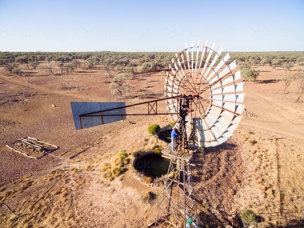 Image of Aerial view of man repairing windmill - Austockphoto