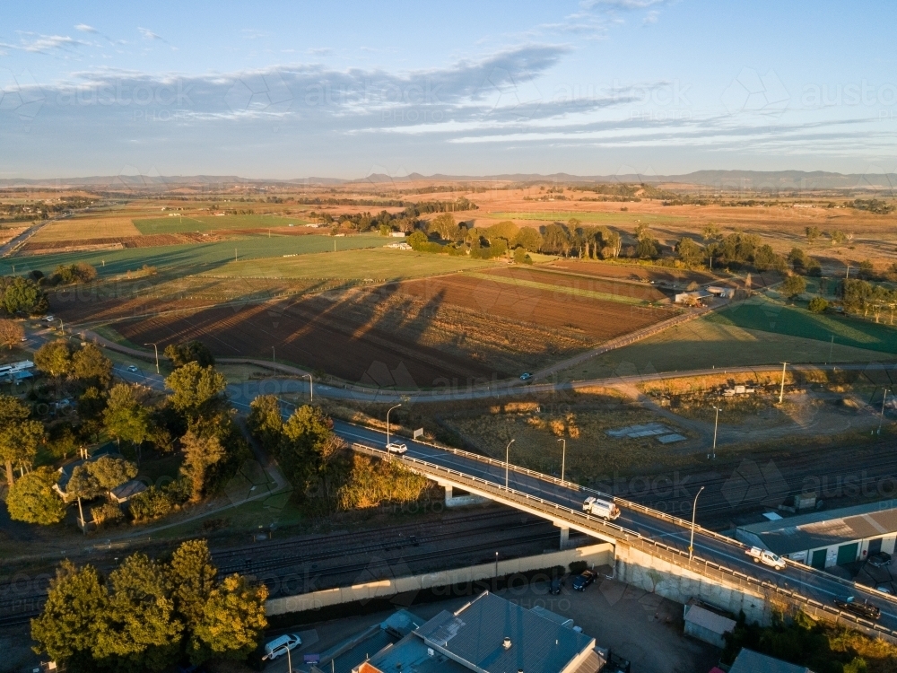 Image of Aerial view of morning light on bridge over railway heading ...