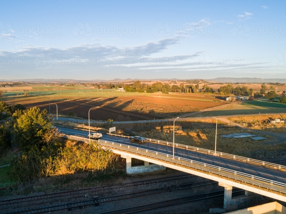 Image of Aerial view of morning light on bridge over railway heading ...