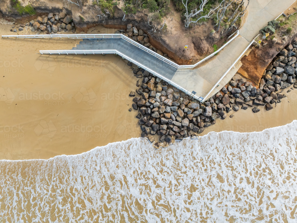 Image of Aerial view of ocean waves on a beach below a coastal jetty ...