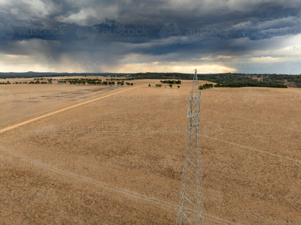 Image of Aerial view of power stanchions in a dry paddock under dark ...