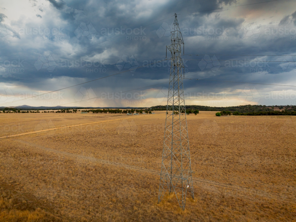 Image of Aerial view of power stanchions in a dry paddock under dark ...