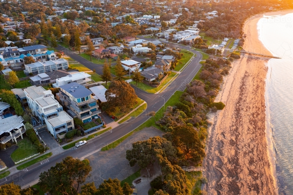 Image of Aerial view of residences in coastal town adjacent a beach at ...