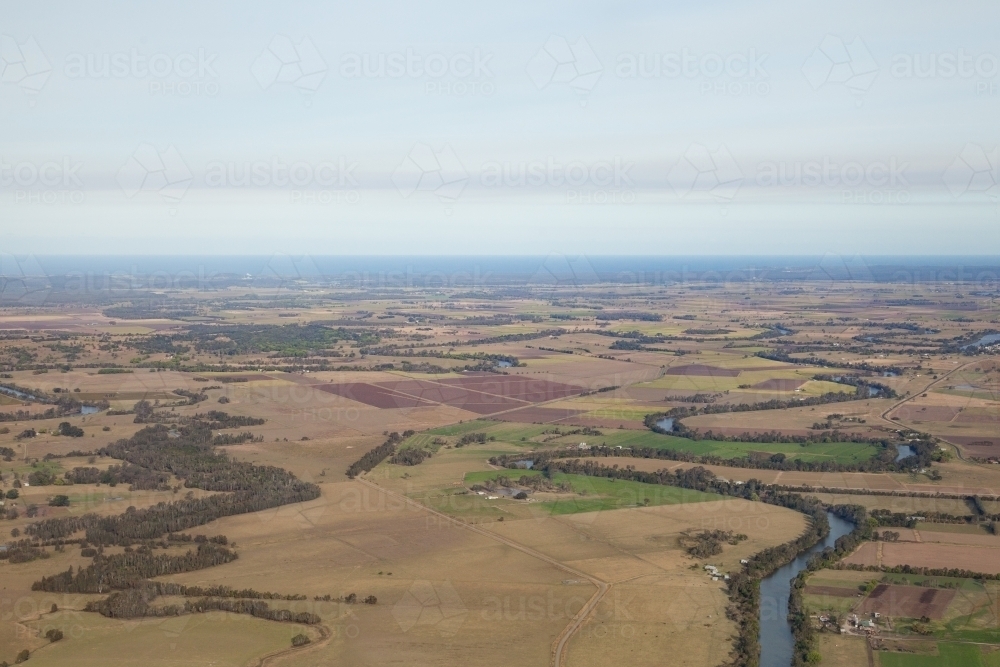 Image of Aerial view of river winding through farm land in the country ...