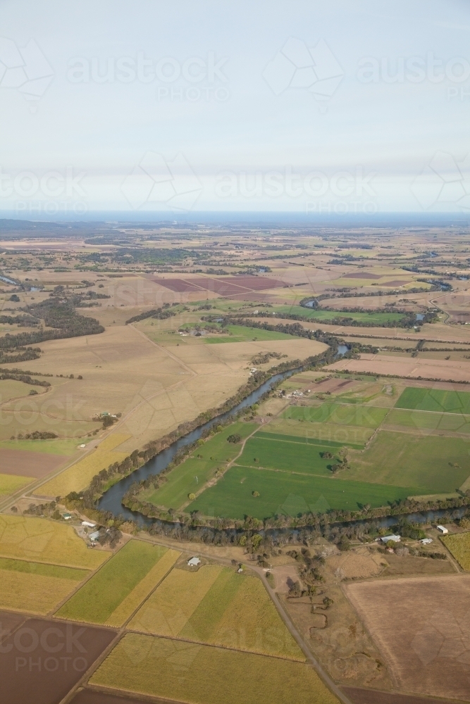 Image of Aerial view of river winding through farm land in the country ...