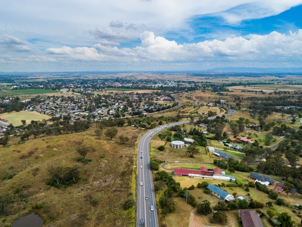 Image of aerial view of road heading into town with properties and ...