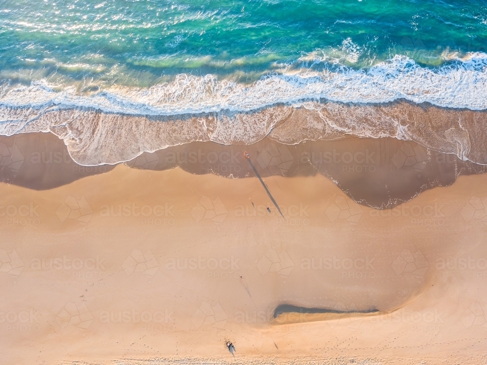 Image of Aerial view of shadows and waves on a sandy beach - Austockphoto