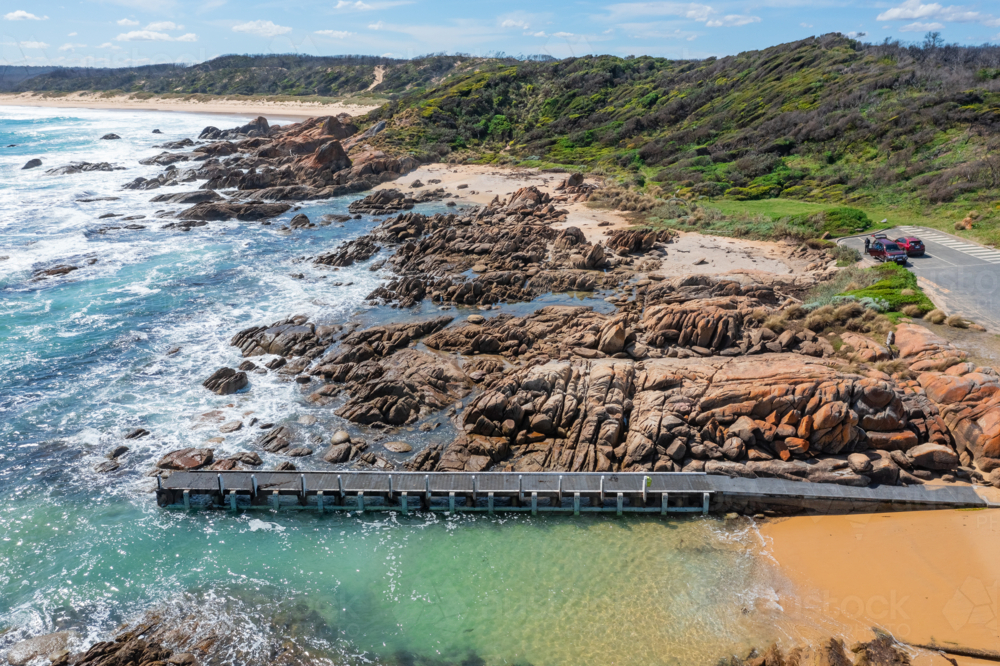 Image of Aerial view of small jetty and small beach amongst a rocky ...