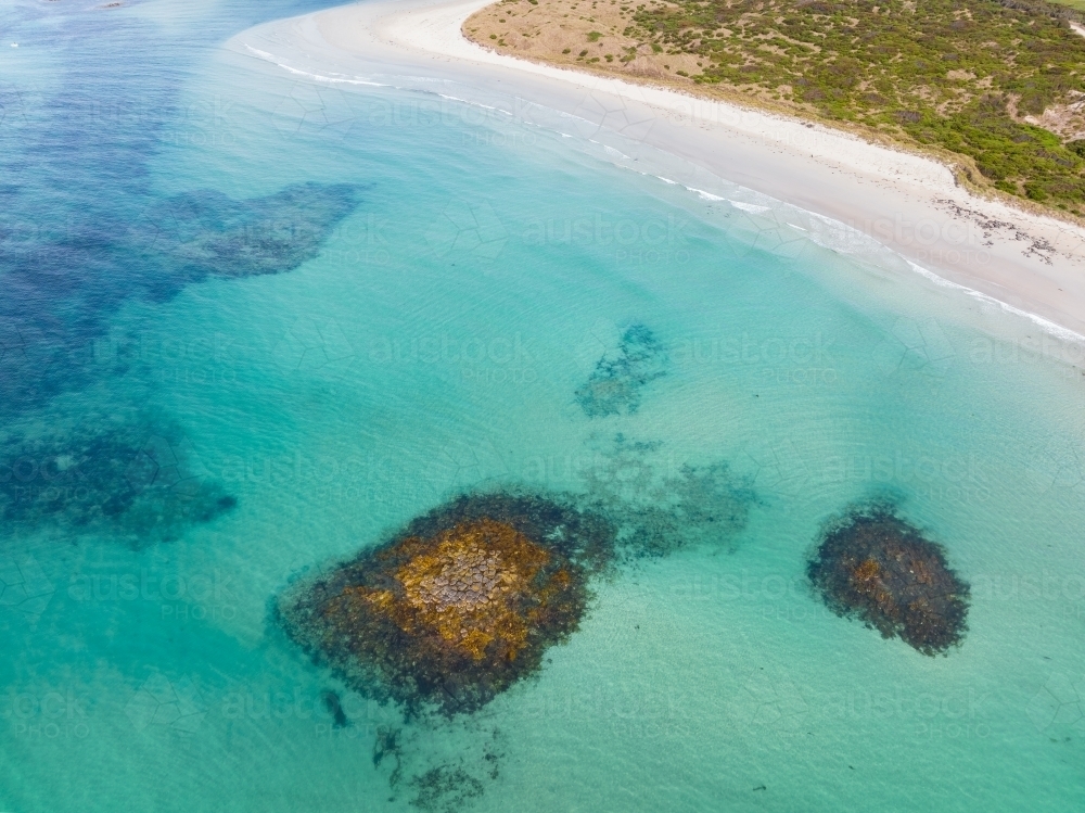 Image of Aerial view of small rocky reefs in turquoise blue water off a ...