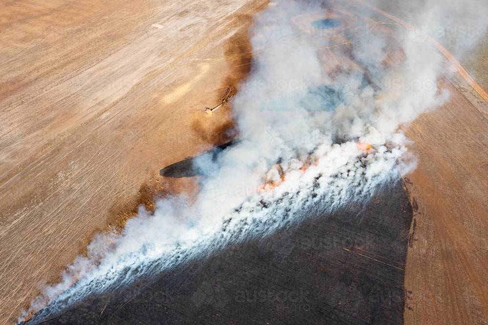 Image of aerial view of stubble fire with white smoke and blackened ...