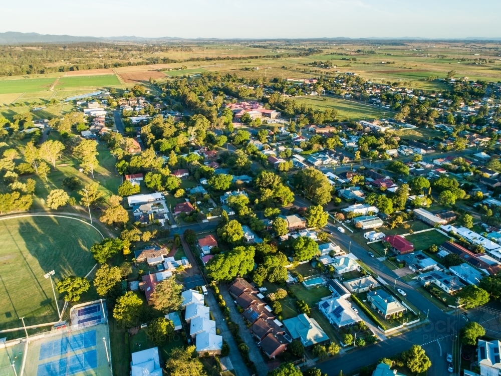 Image of Aerial view of sunset light over lush small aussie town with ...