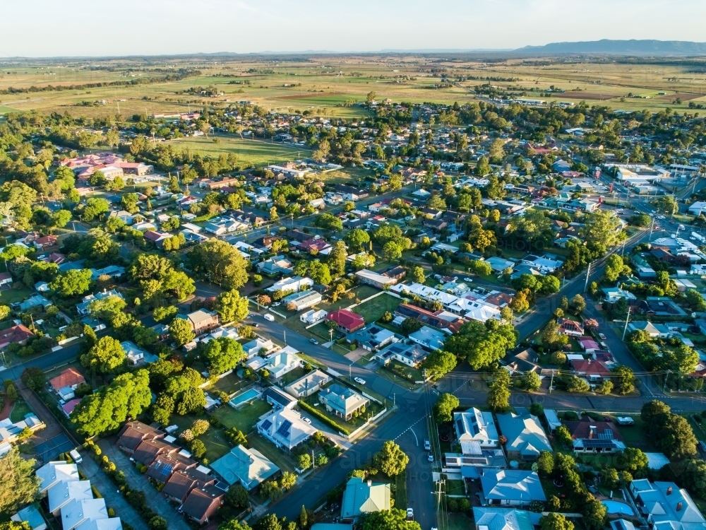 Image of Aerial view of sunset light over lush small aussie town with ...