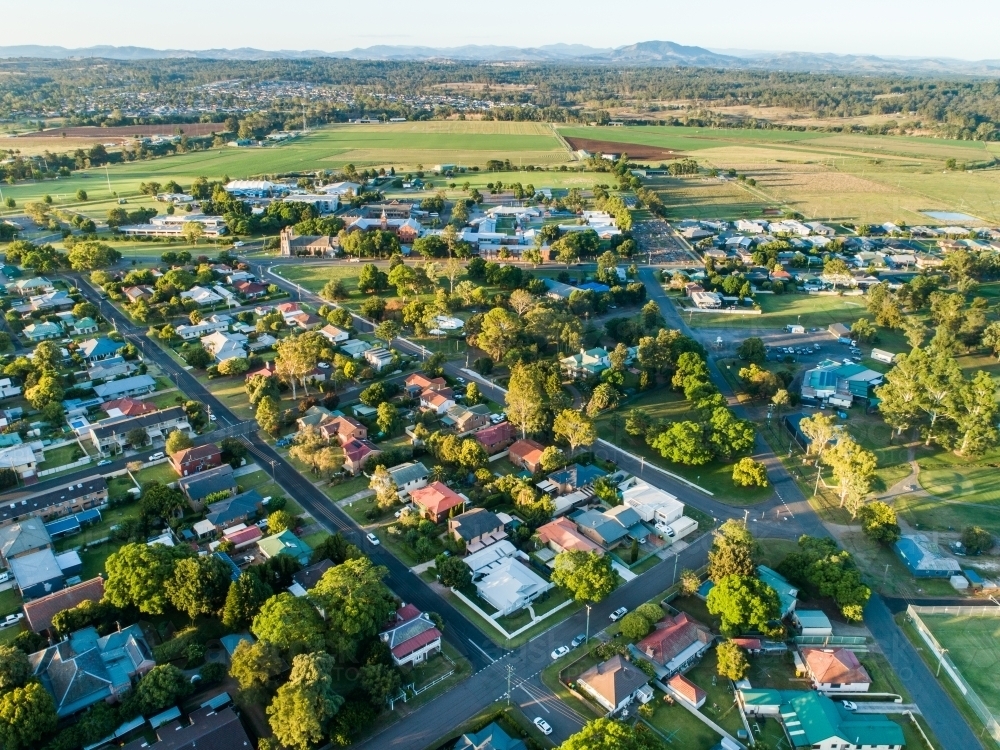 Image of Aerial view of sunset light over lush small aussie town with ...