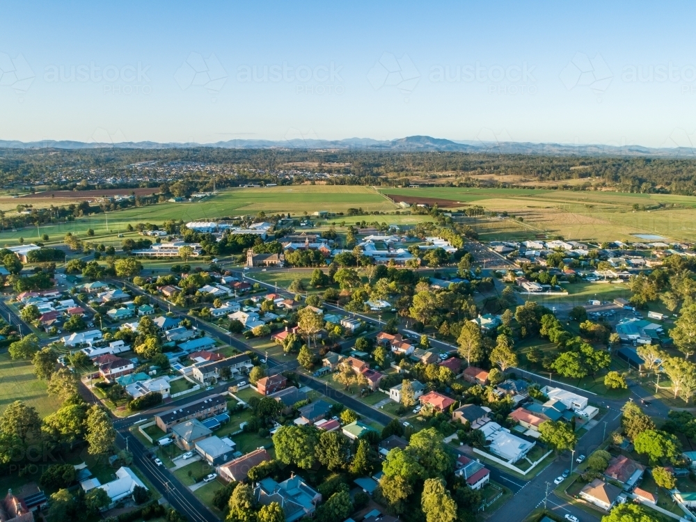 Image of Aerial view of sunset light over lush small aussie town with ...