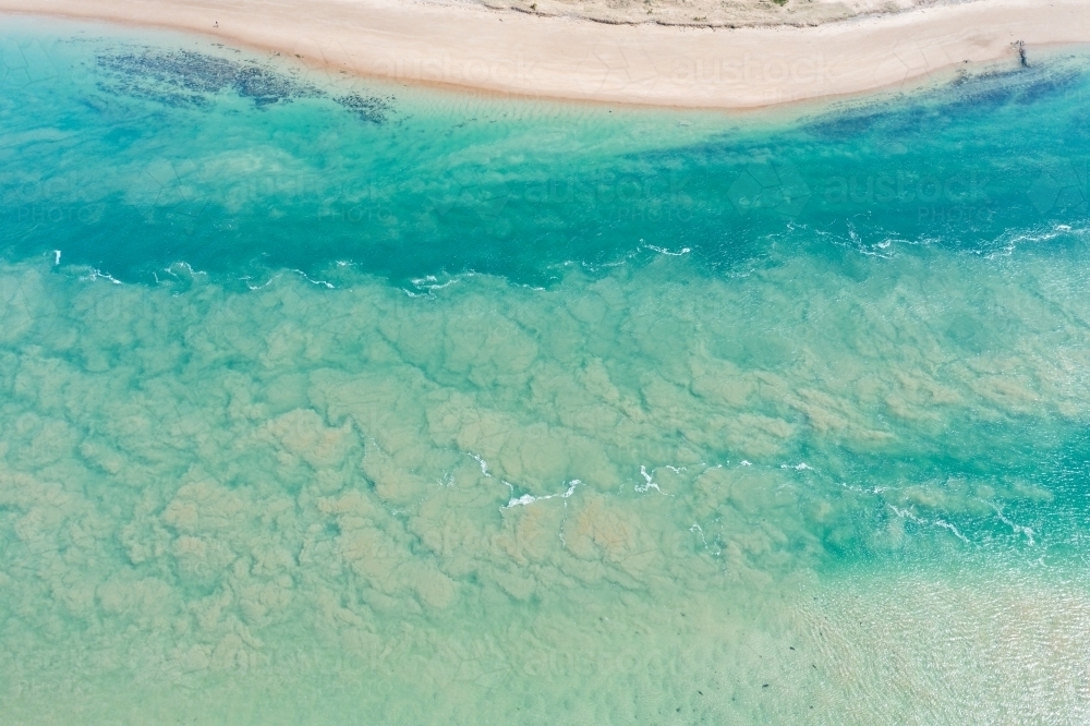 Image of Aerial view of swirling water and sand patterns in a shallow ...