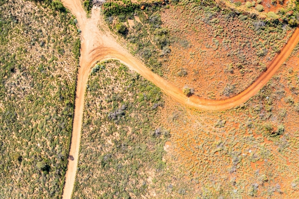 Image of aerial view of the curve of a sandy track with coastal scrub ...