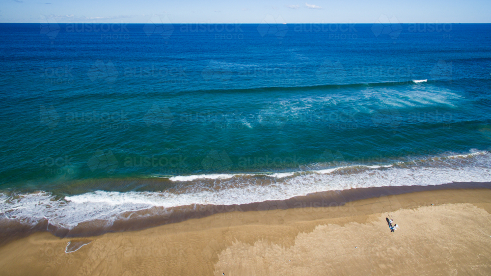 Image of Aerial view of two men surf fishing from the beach as waves ...
