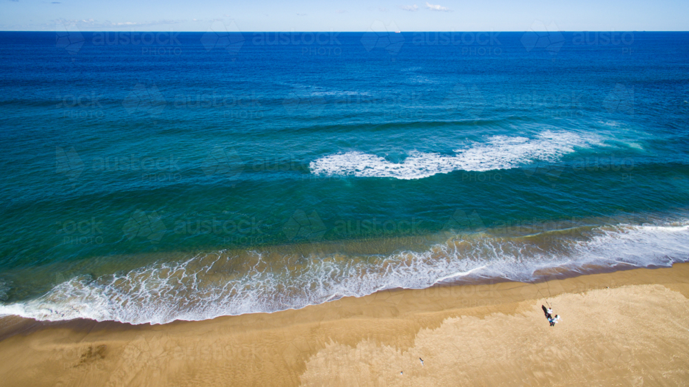 Image of Aerial view of two men surf fishing from the beach as waves ...