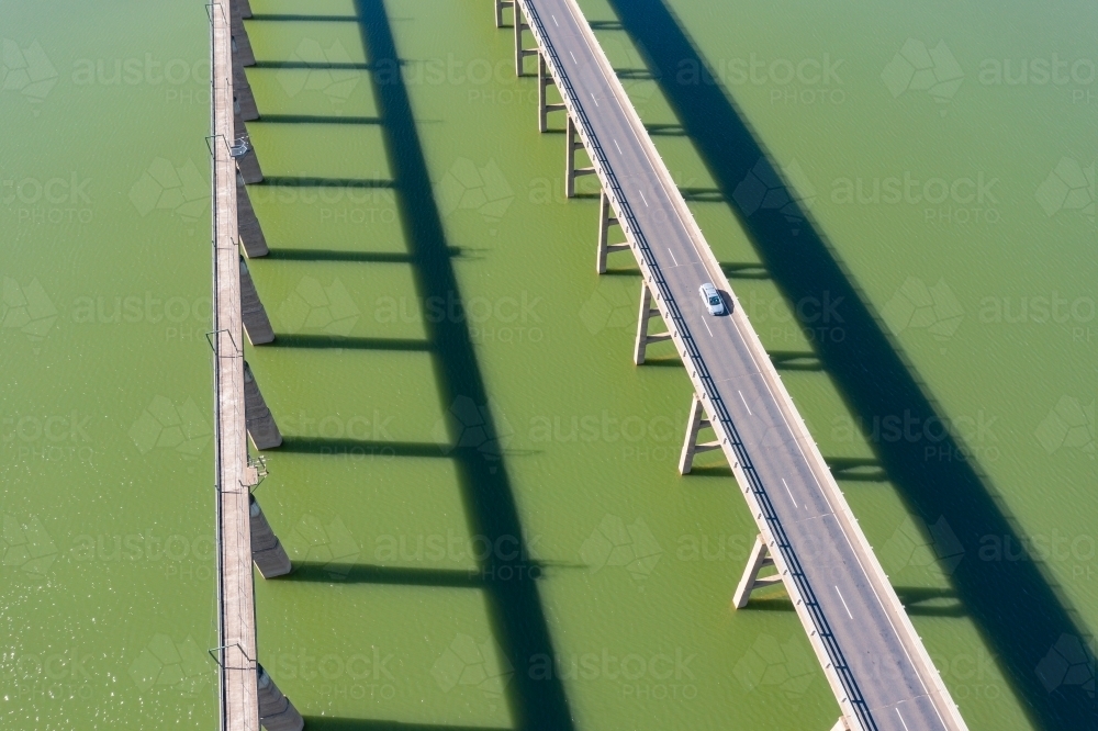 Image of Aerial view of two parallel bridges casting shadows over the ...