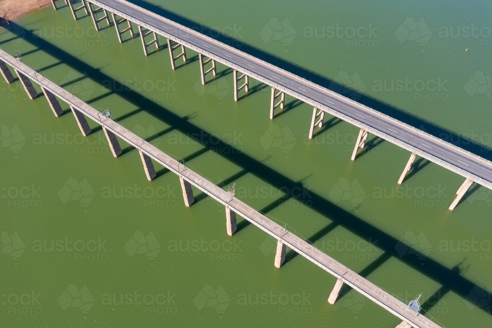 Image of Aerial view of two parallel bridges casting shadows over the ...
