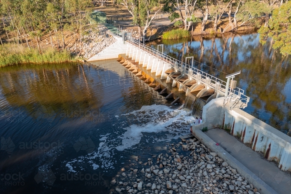 Image of Aerial view of water flowing over a weir on a dirty brown ...