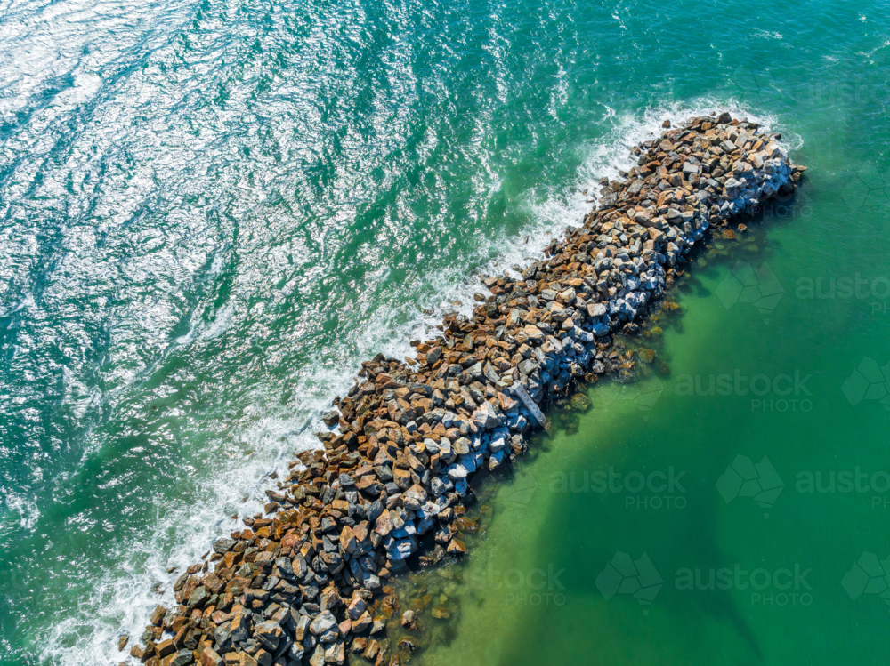 Image of Aerial view of waves breaking on a long rocky breakwater ...