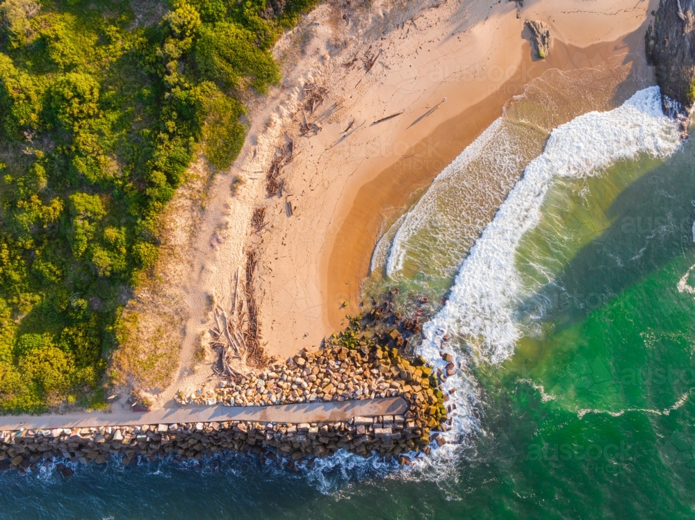 Image of Aerial view of waves breaking on a small isolated beach with a ...