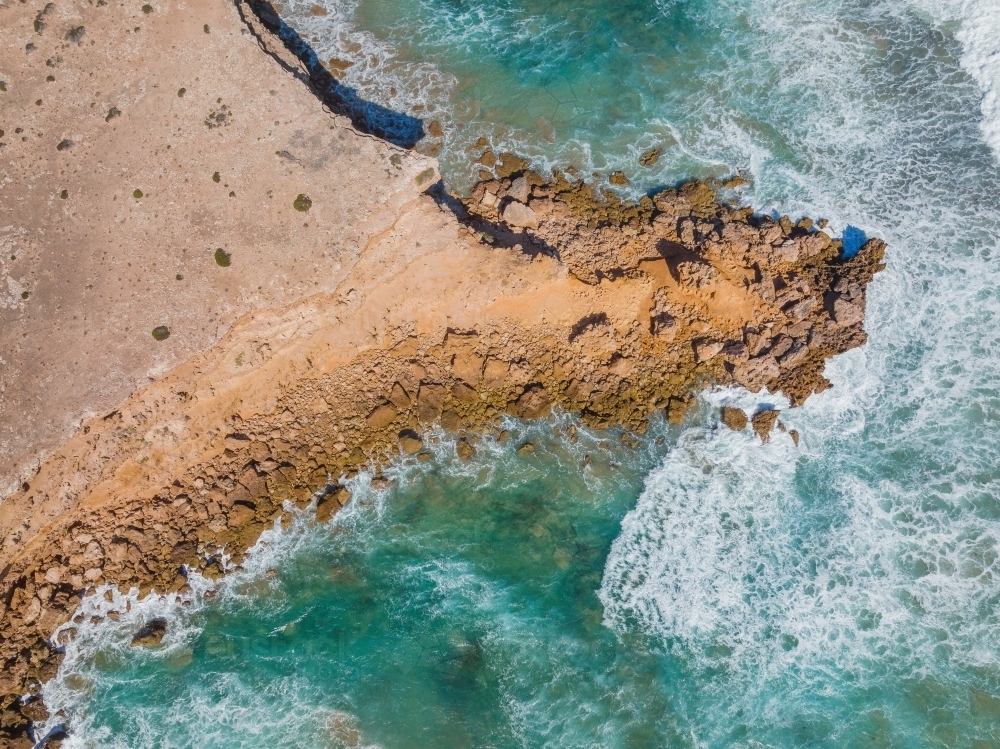 Image of Aerial view of waves crashing against eroded cliffs along a ...