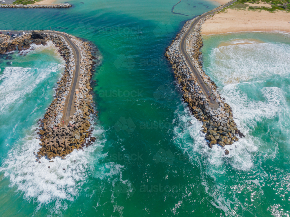 Image of Aerial view of waves crashing onto rocky breakwaters at the ...