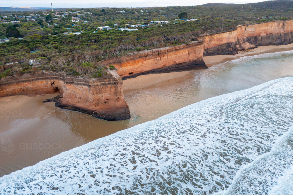 Image of Aerial view of waves on a beach below eroded coastal cliffs ...