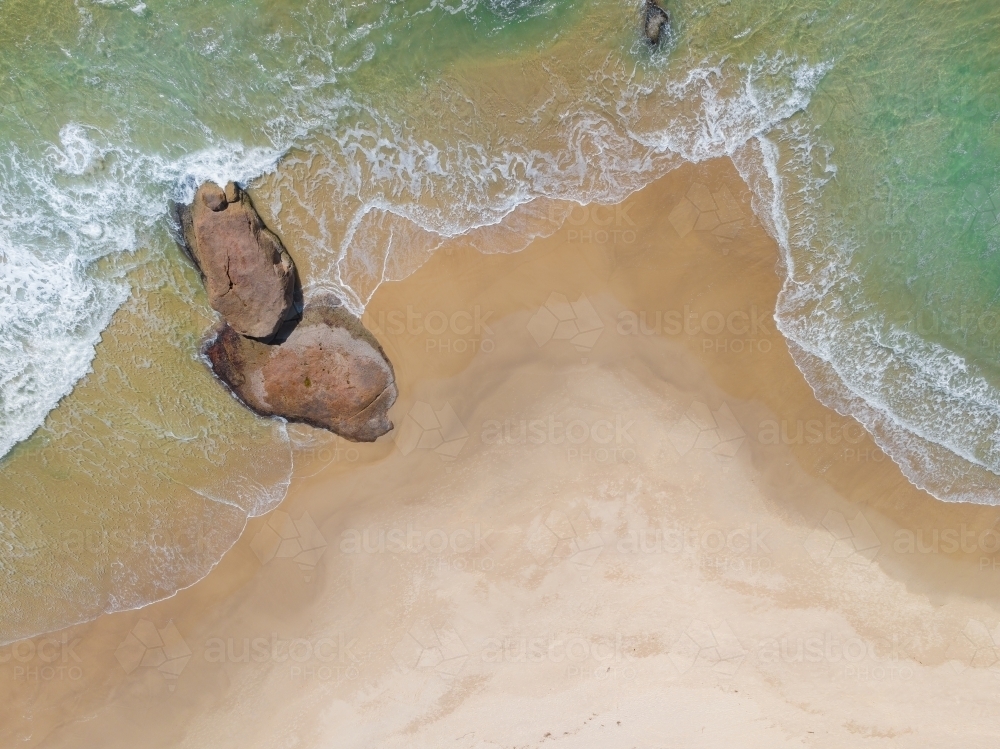 Image of Aerial view of waves washing over large granite boulders on a ...