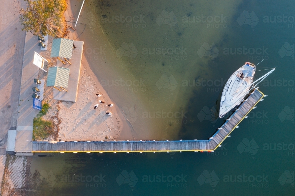 Image of Aerial view over a single yacht tied to an angled jetty off a ...