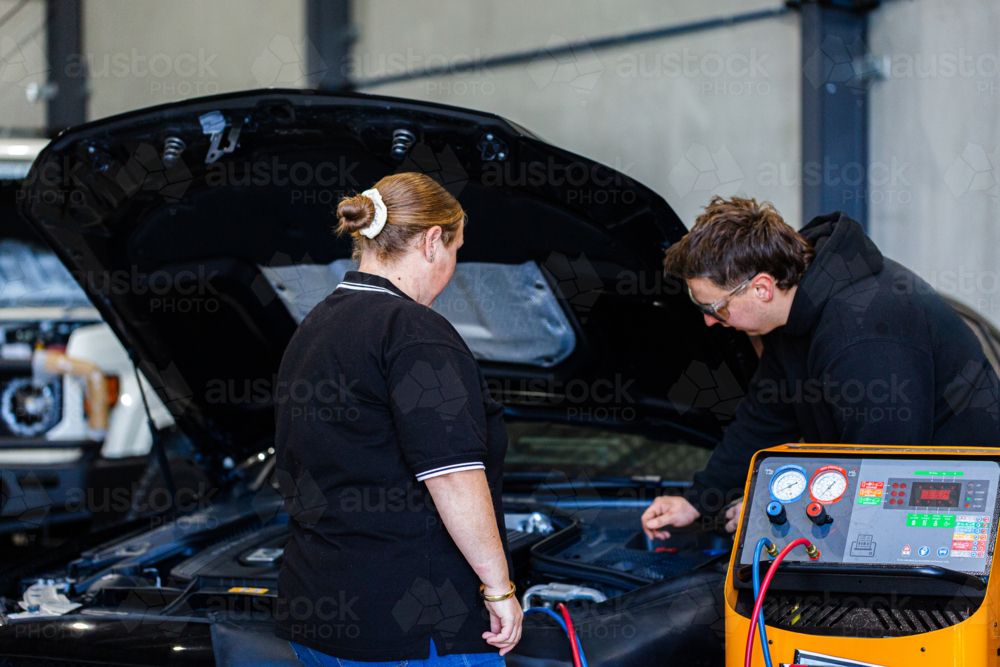 Image of air conditioner technician talking with customer about car in ...