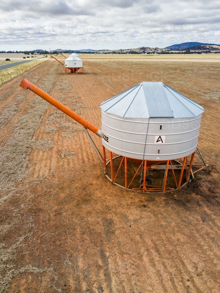 Image of An aerial view of grain bins in a paddock - Austockphoto