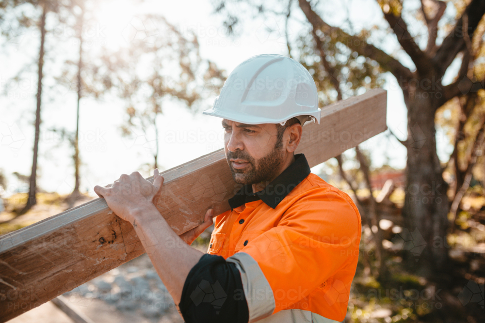 Image of An Aussie man carrying a piece of lumber on his shoulder at a ...