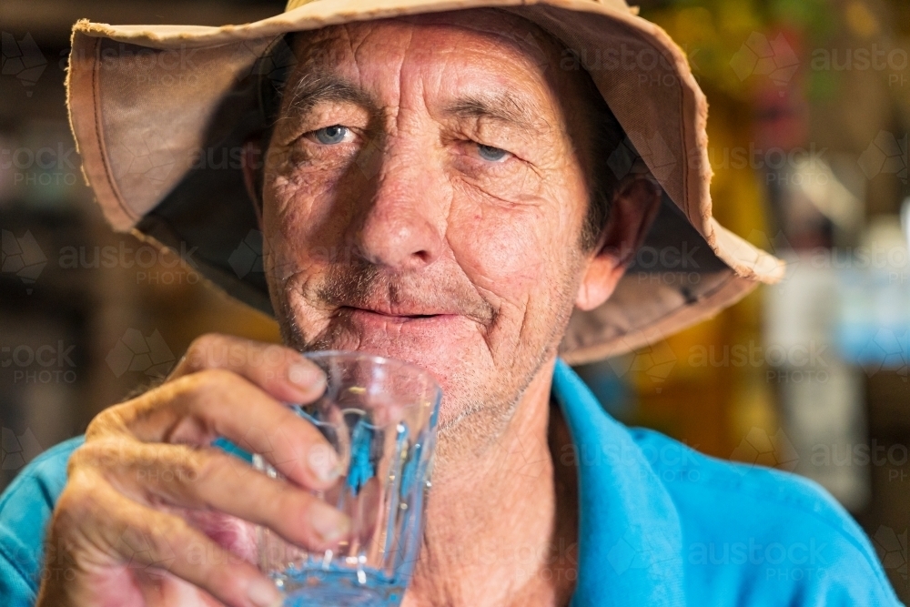 Image of An elderly man wearing a floppy hat smiling and holding a ...