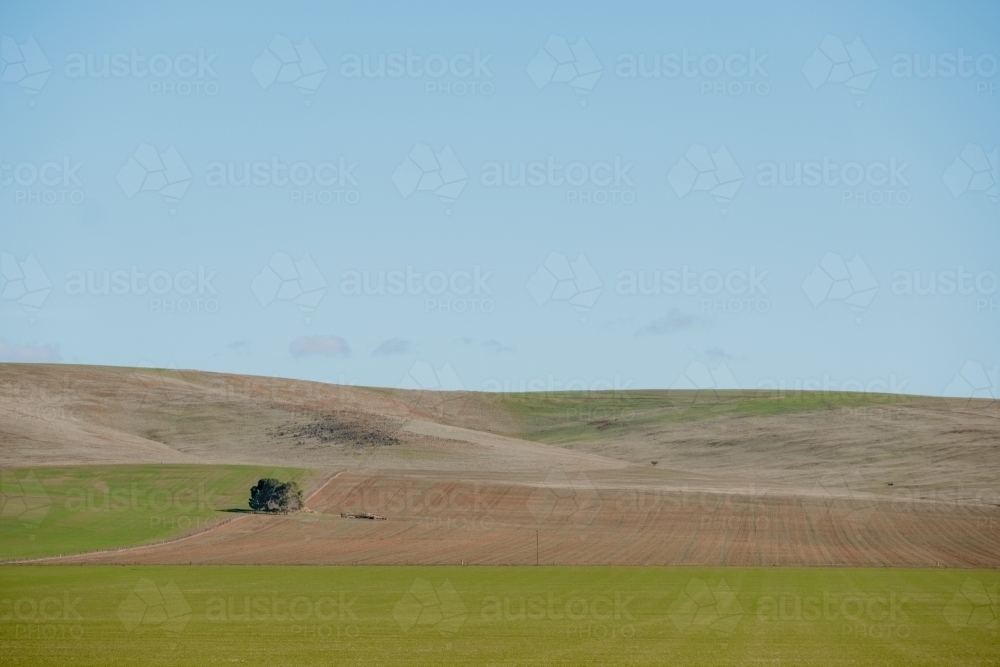 Image of An empty farm paddock with hill background - Austockphoto