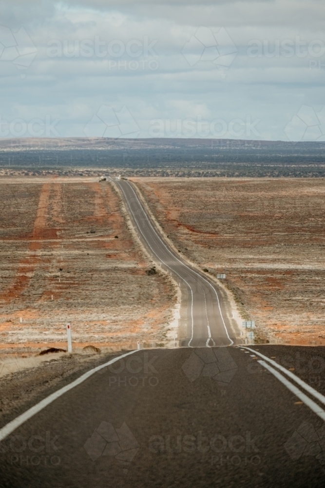 Image of An empty long road through outback - Austockphoto