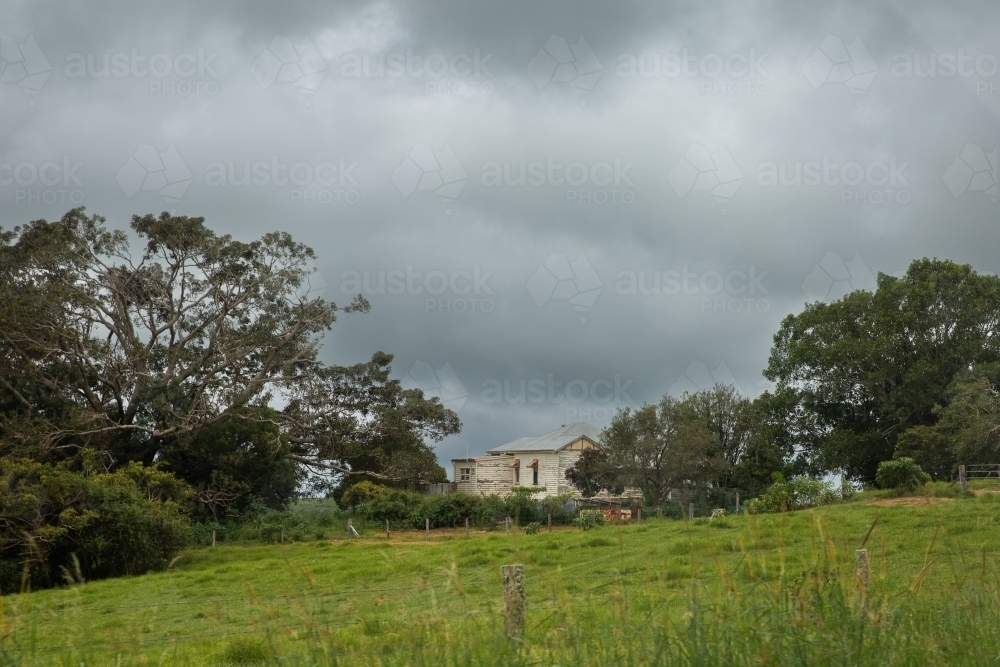 Image of an old farmhouse under an overcast sky - Austockphoto