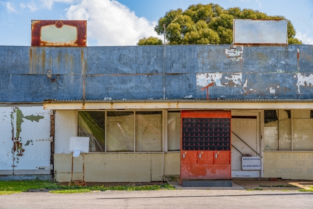 Image of An old shop front with boarded up windows and post office ...