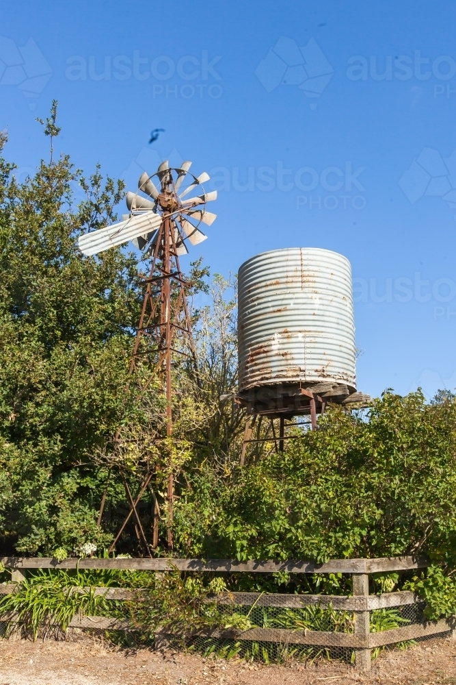 Image of An old water tank and wind mill - Austockphoto