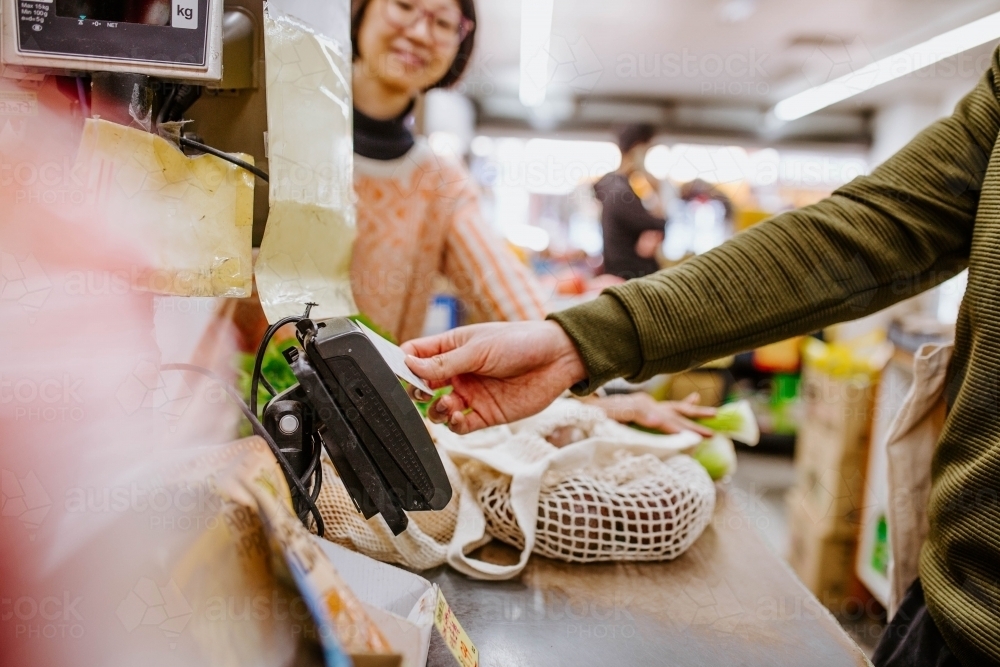 Image of Arm of man paying by card at supermarket counter - Austockphoto