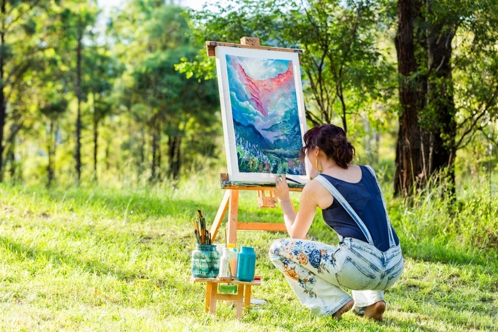 Image of Artist adding fine detail to painting with white brush ...