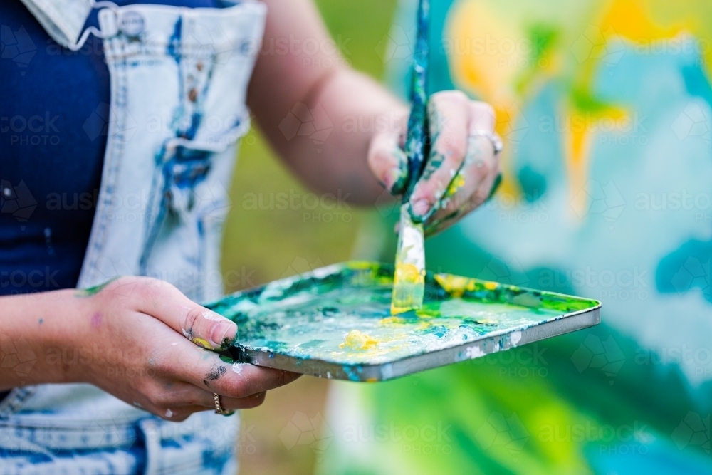 Image of Artists hands mixing paint colours on palette - Austockphoto